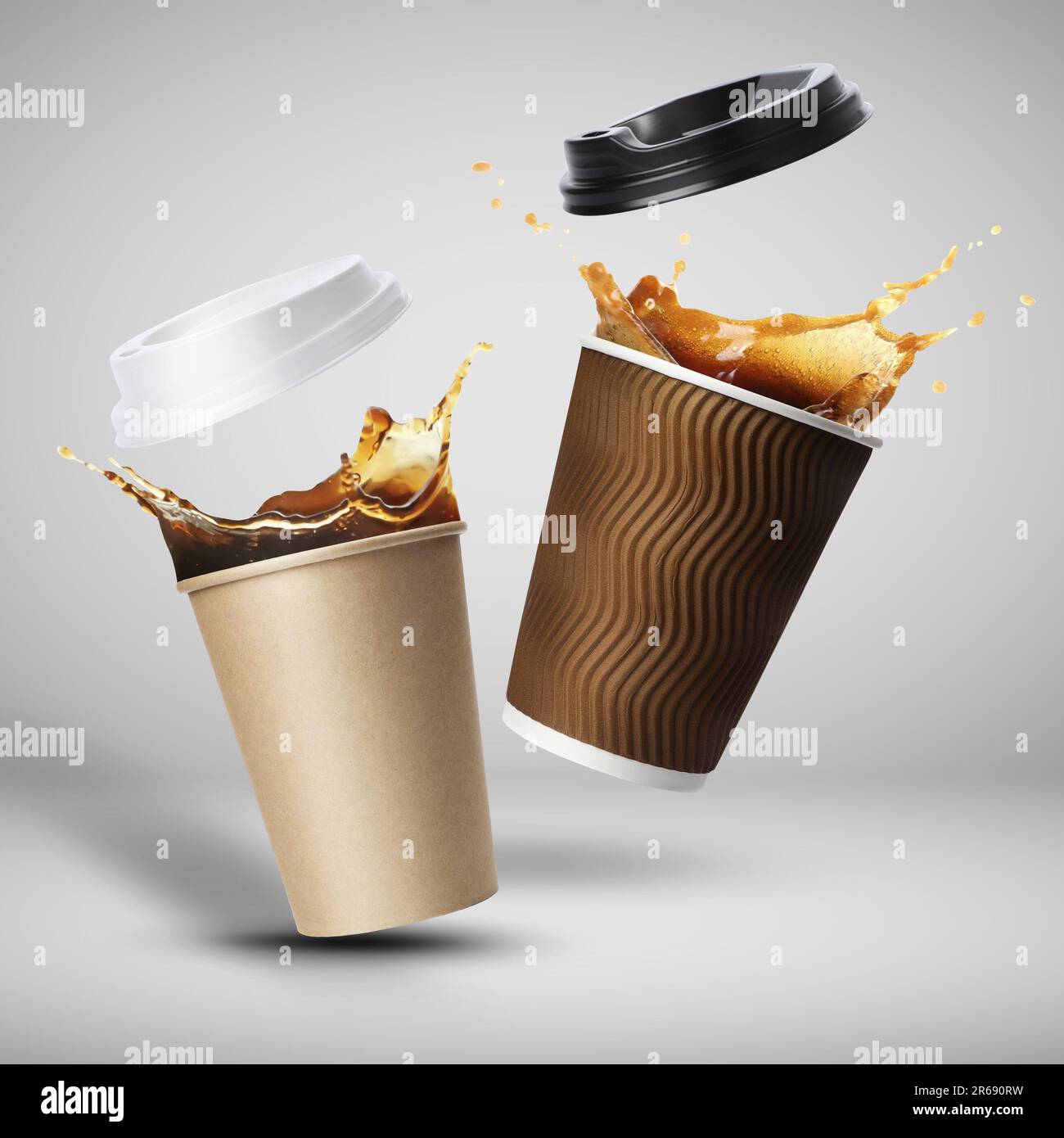 Takeaway paper cups with splashing coffee falling on light grey ...