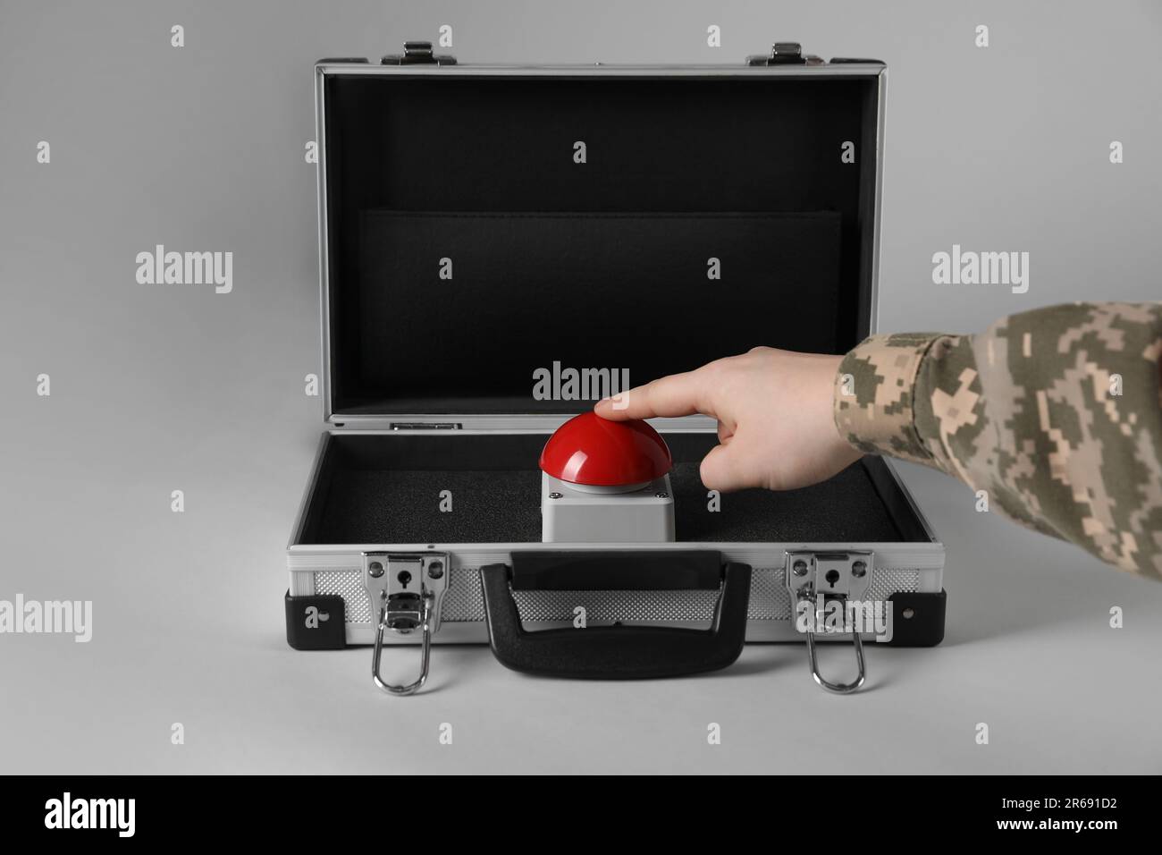 Serviceman pressing red button of nuclear weapon on light gray ...