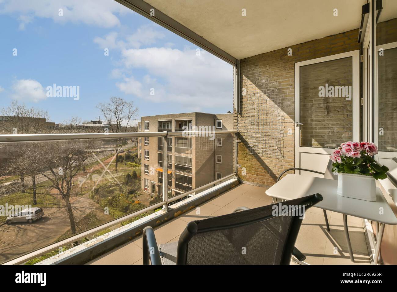 a balcony with flowers on the table and chairs looking out at the city ...