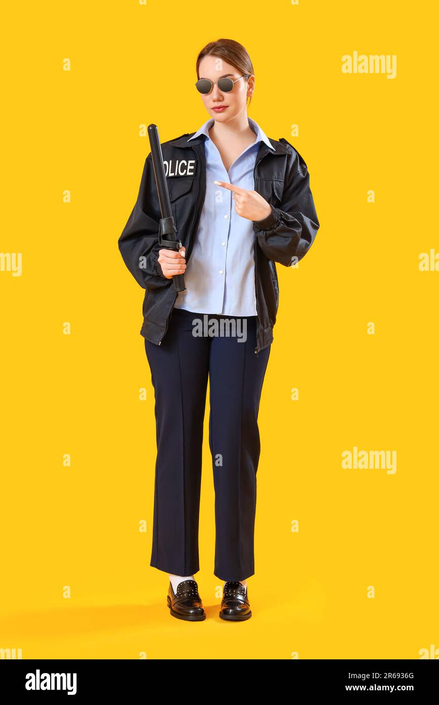 Female police officer with baton on yellow background Stock Photo - Alamy