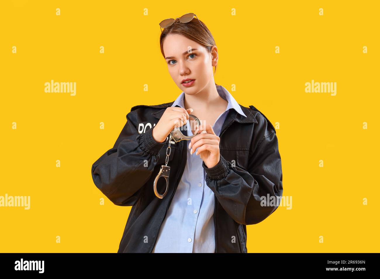 Female police officer with handcuffs on yellow background Stock Photo ...