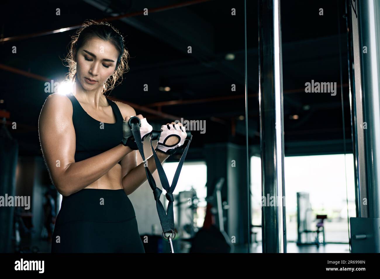 Sporty woman exercising on multistation at gym for arm and shoulders ...