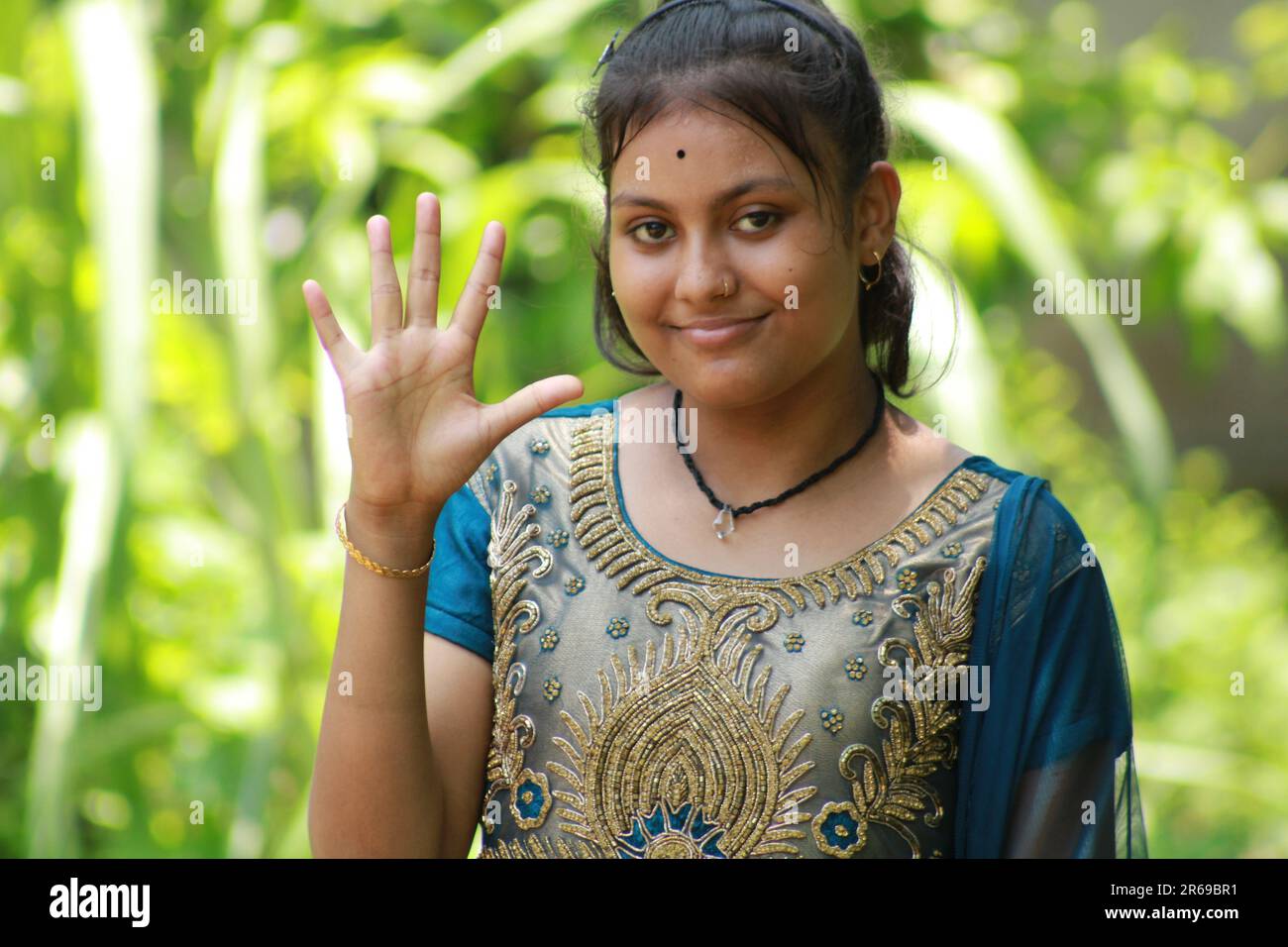 Indian Teenage Girl showing and pointing with finger number five while ... Indian Teenage Girl showing and pointing with finger number five while ...