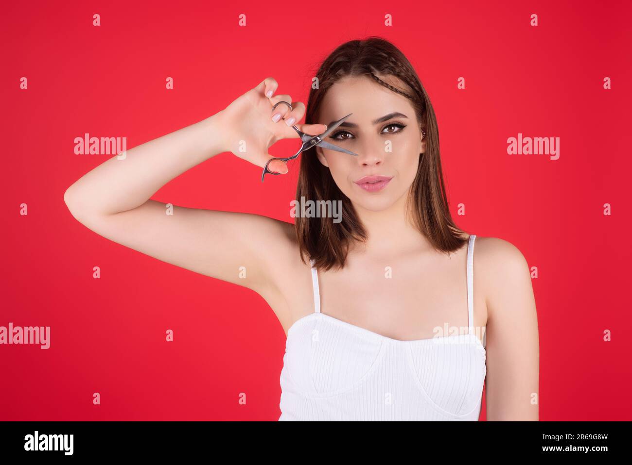 Haircut. Portrait of young woman hairdresser cutting hair with scissors ...