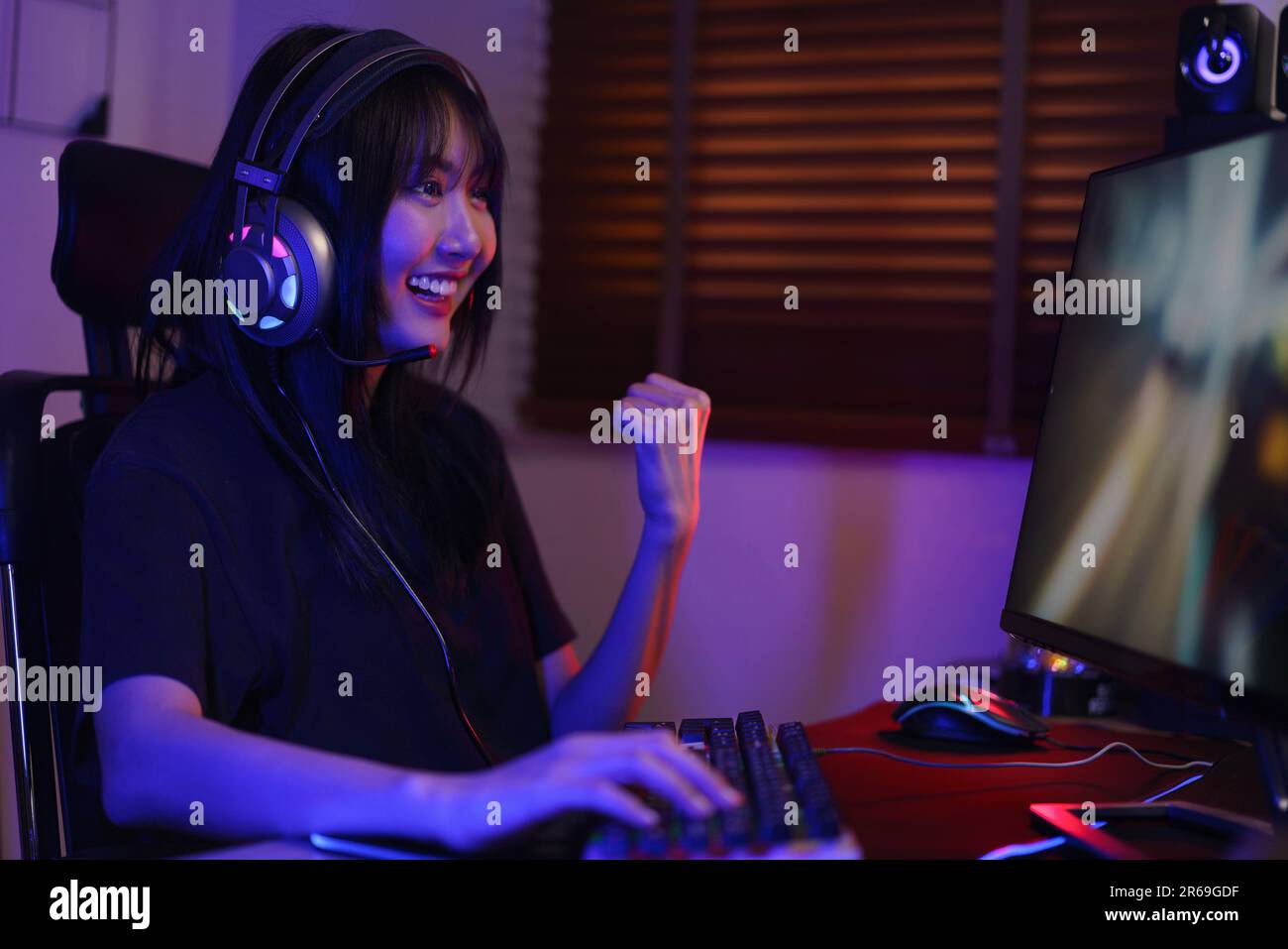 Female cyber hacker gamer watching monitor and making win gesture after ...