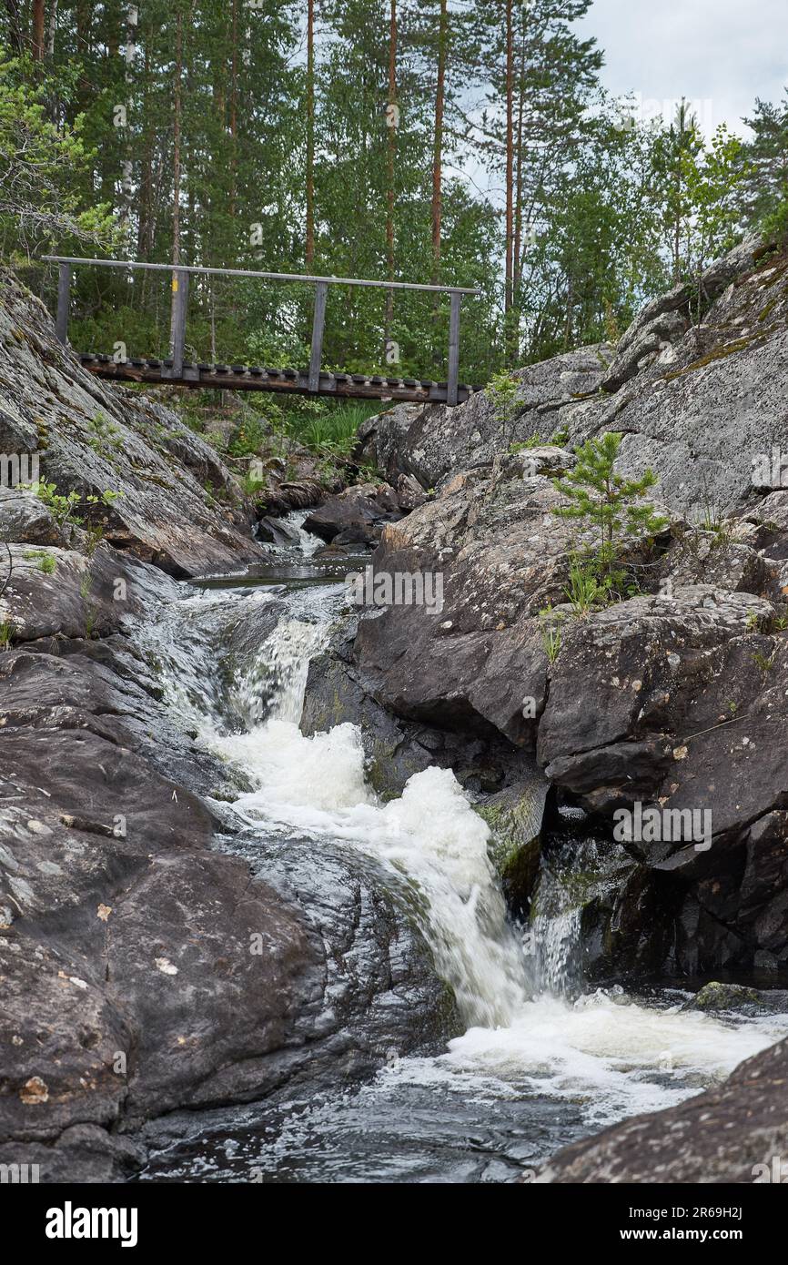 A small bridge between rocks going over a streaming brook in a forest ...