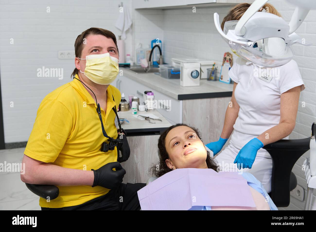 Professional male dental hygienist and patient look at a screen ...