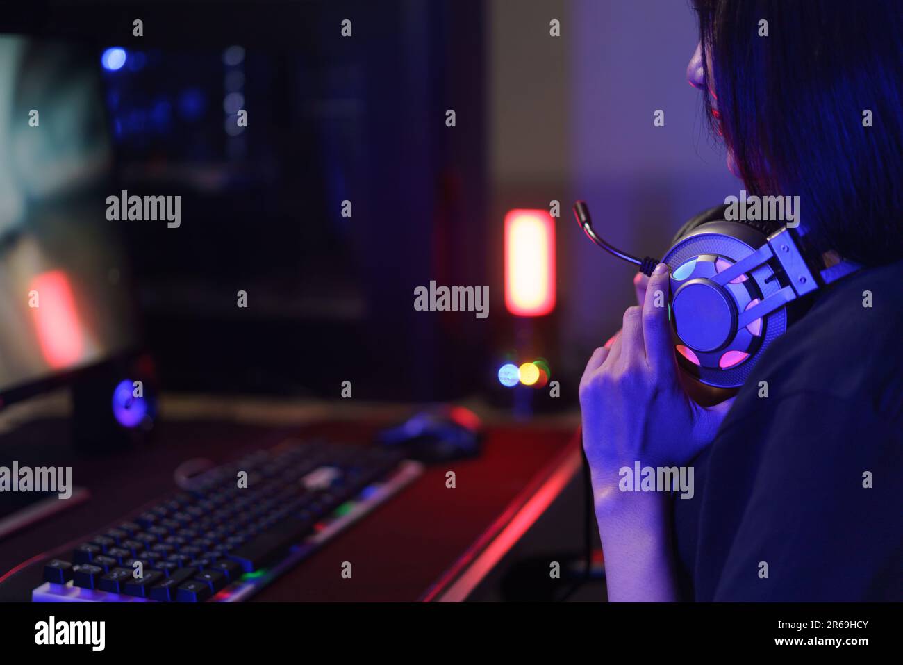 Female cyber hacker gamer in headphone around neck watching video games on monitor with having ...