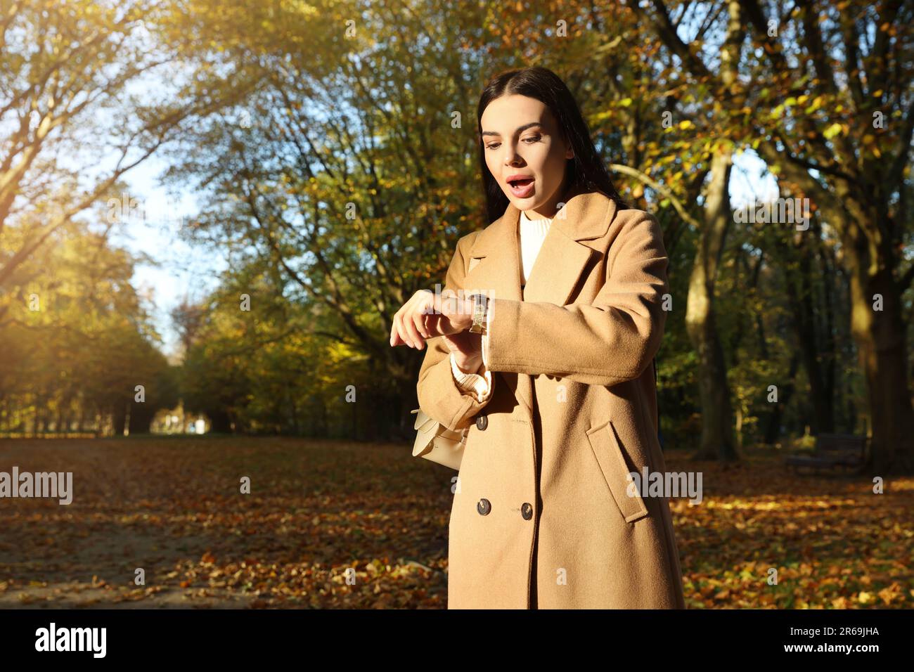 Emotional woman checking time on watch in park. Being late concept ...