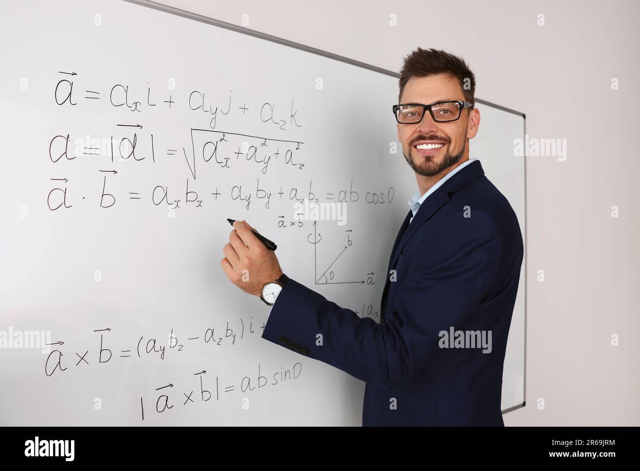 Happy teacher explaining mathematics at whiteboard in classroom Stock ...
