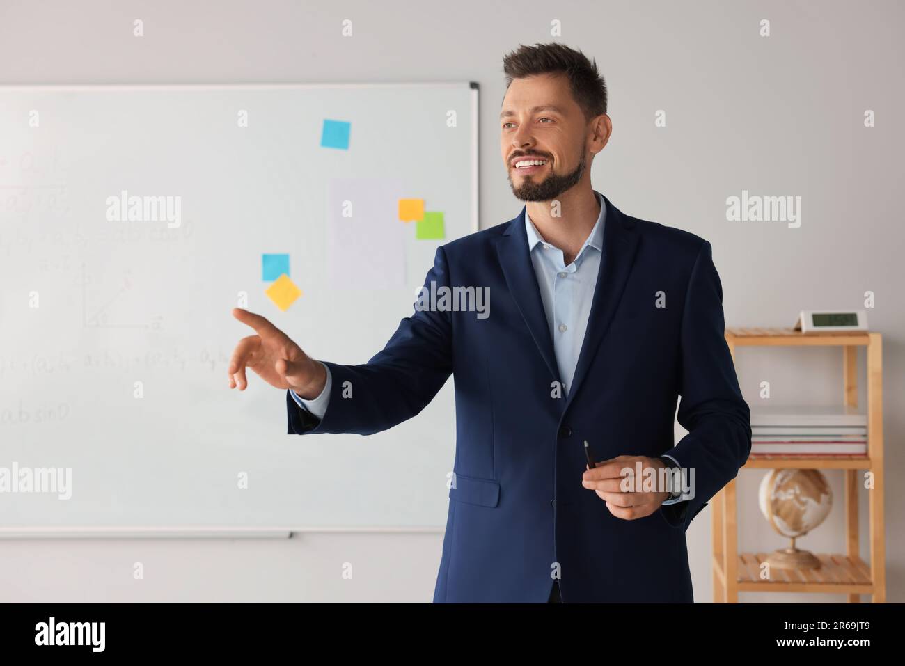 Happy teacher explaining mathematics at whiteboard in classroom Stock ...