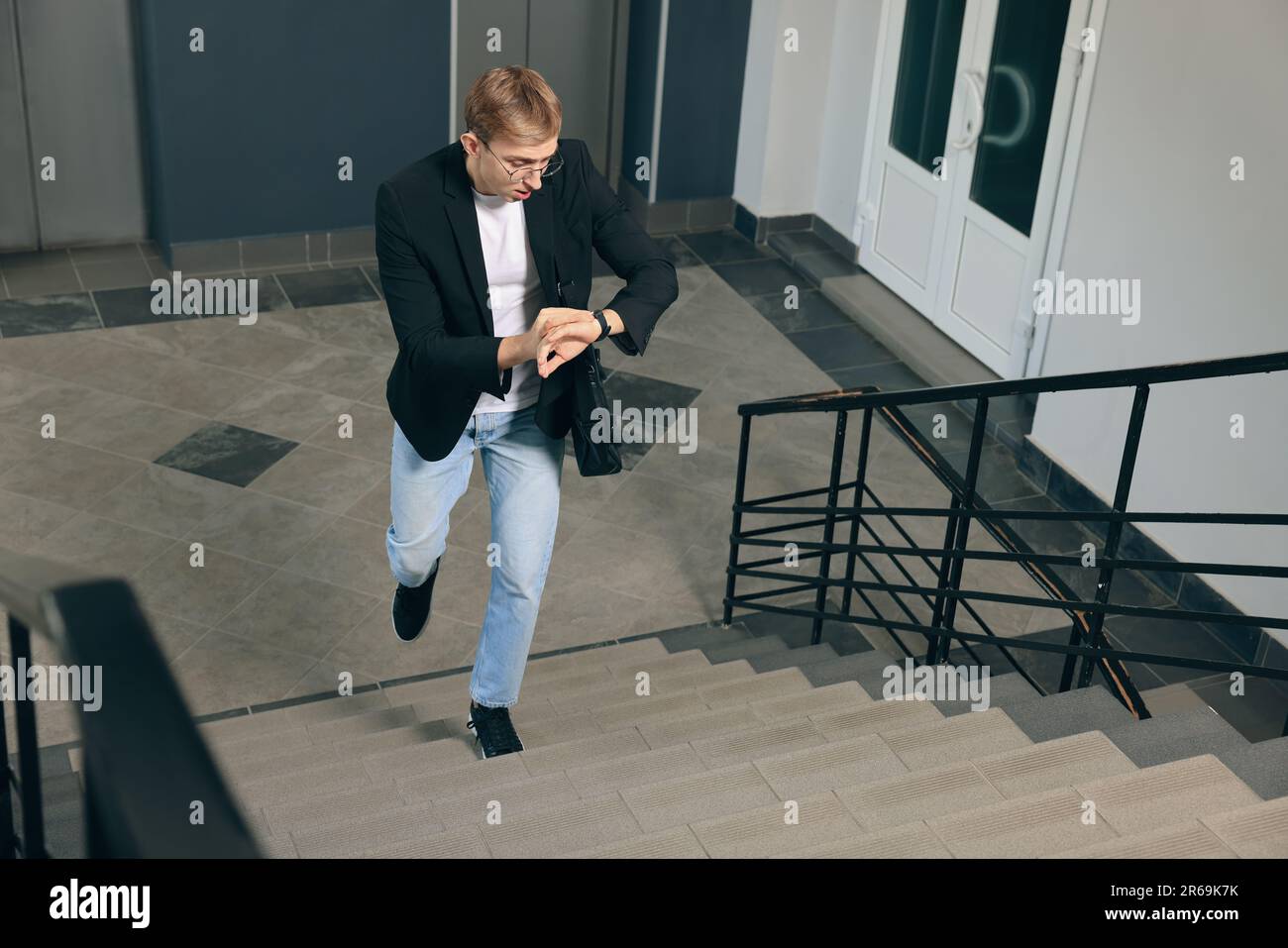 Emotional man checking time while walking up stairs in office. Being ...