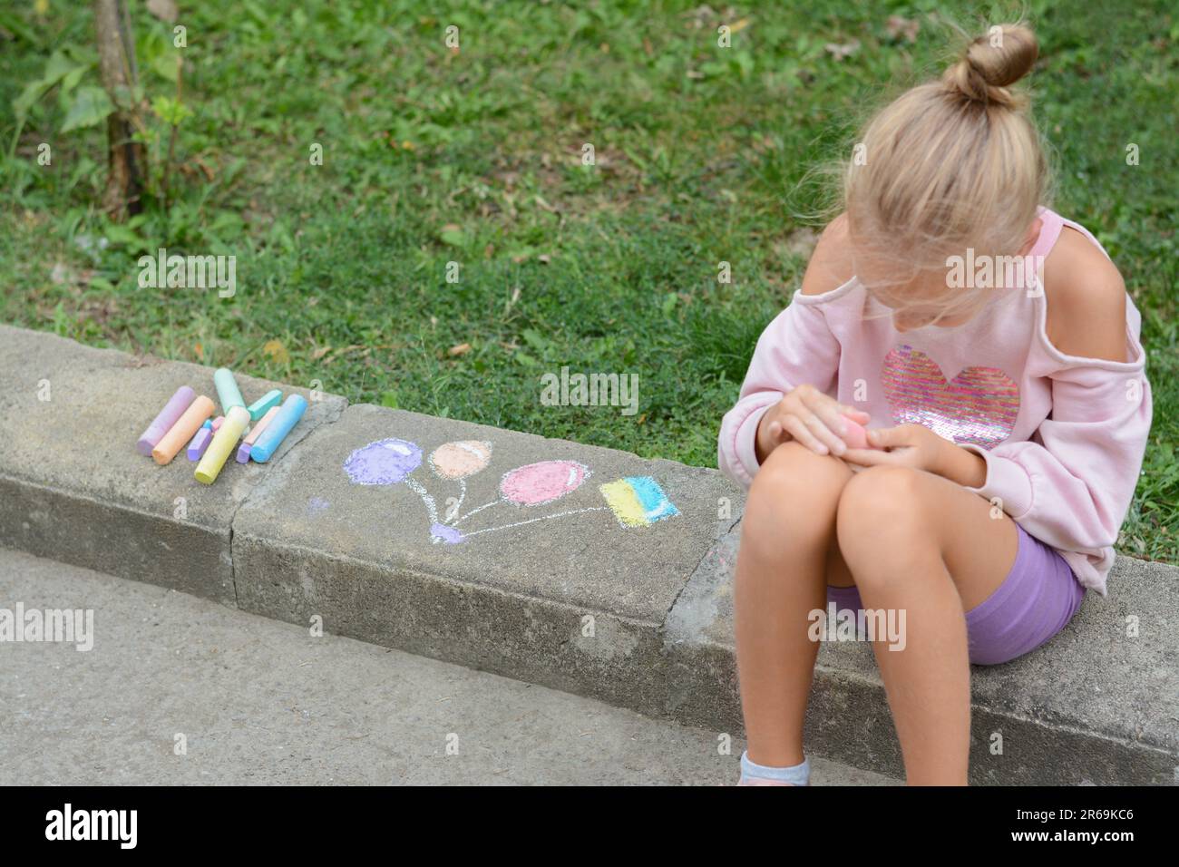 Little child chalk piece sitting on curb outdoors, space for text Stock Photo - Alamy
