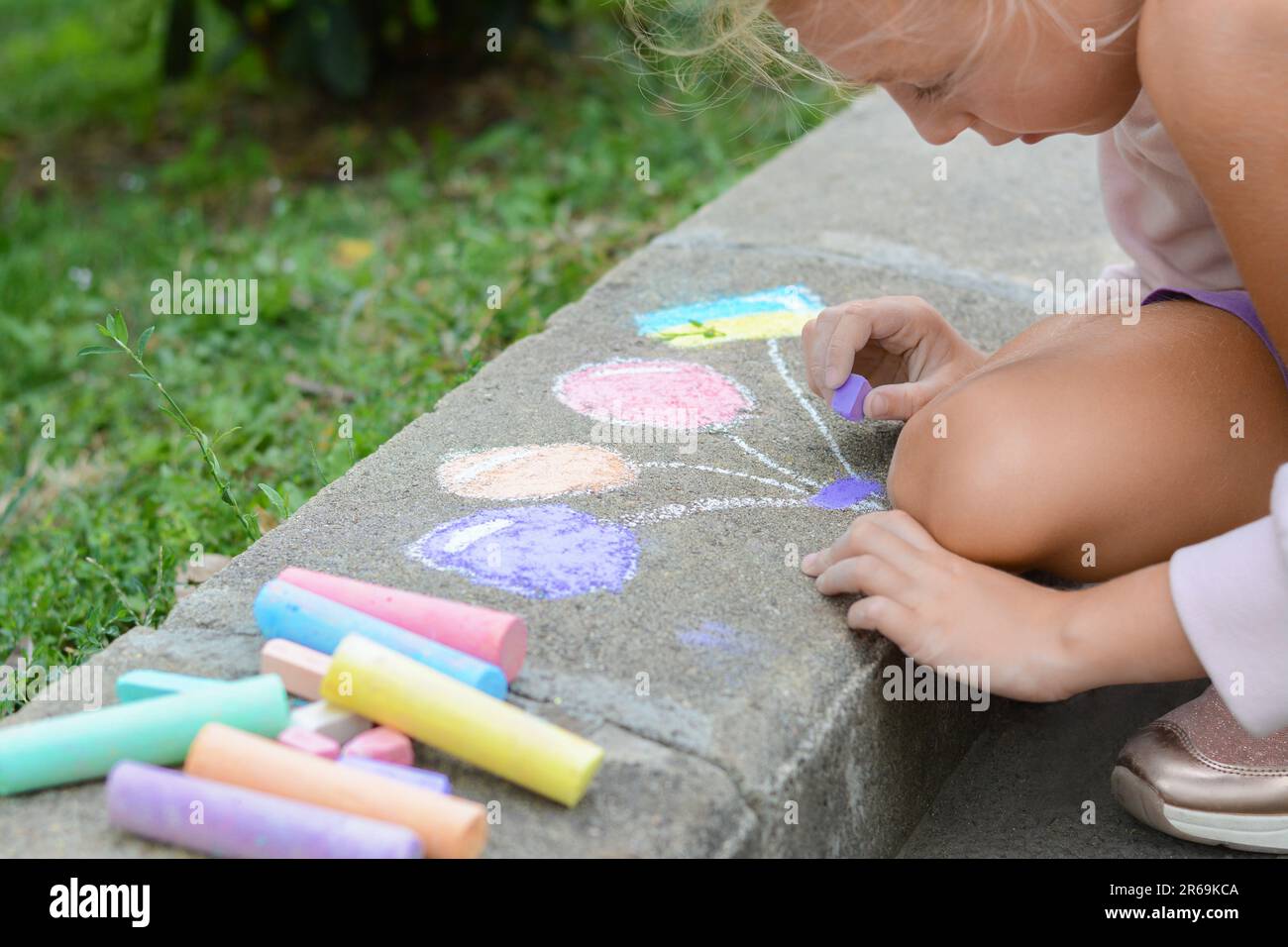 Little child drawing balloons and ukrainian flag with chalk on curb outdoors, closeup Stock ...