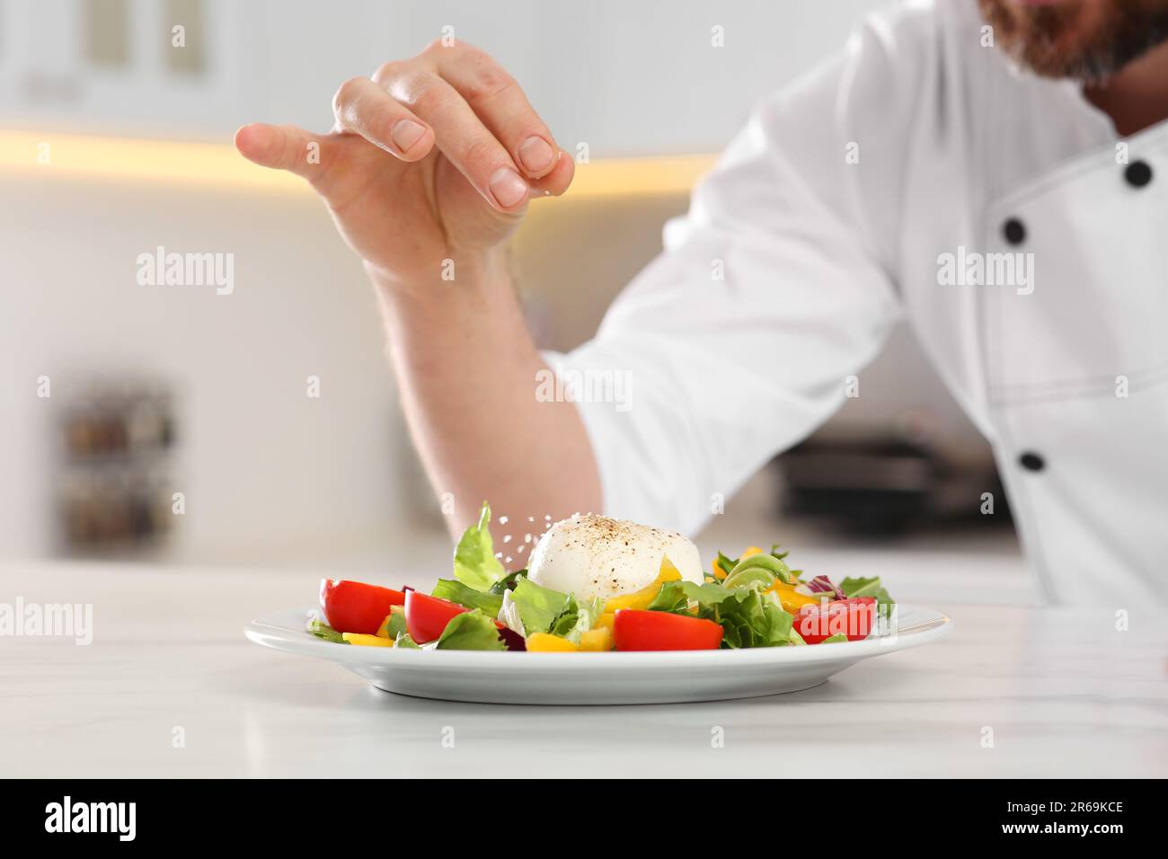 Professional chef salting delicious salad at marble table, closeup ...