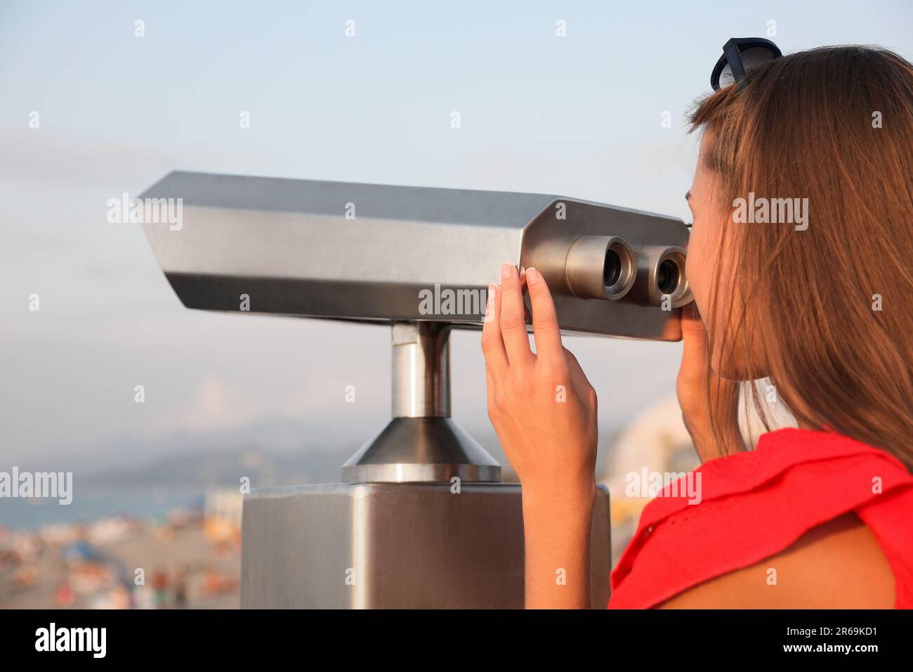 Young woman looking through tourist viewing machine at observation deck ...