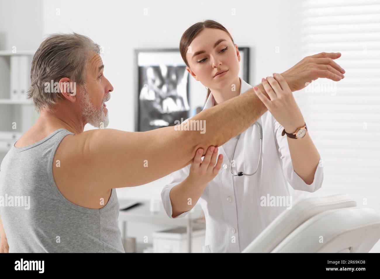 Female orthopedist examining patient's arm in clinic Stock Photo - Alamy
