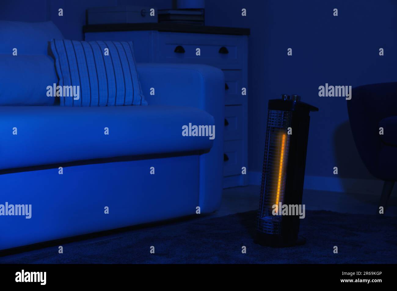 Electric infrared heater in dark living room at night Stock Photo - Alamy