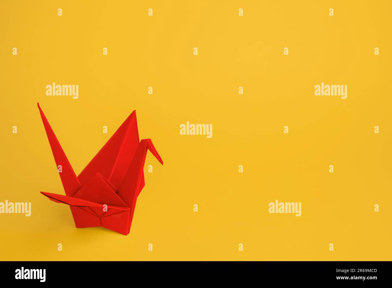 Origami art. Beautiful red paper crane on orange background, space for ...