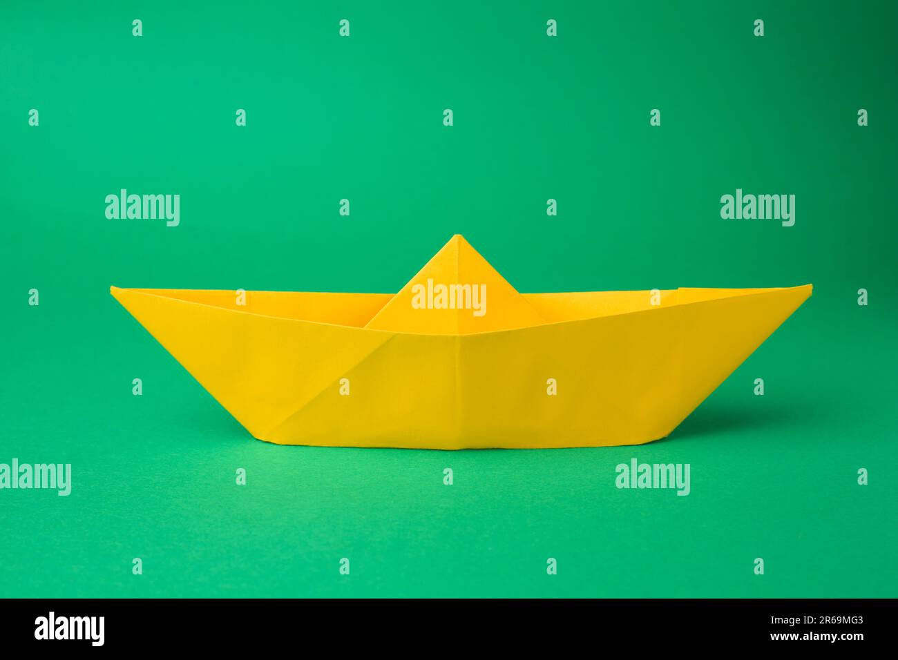 Origami art. Yellow paper boat on green background Stock Photo - Alamy