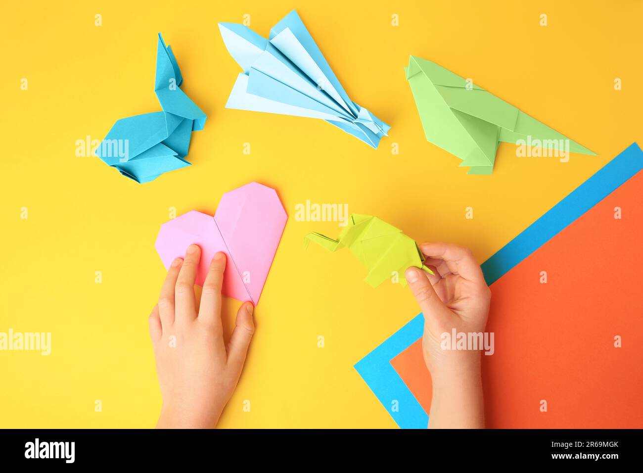 Origami art. Child holding paper figures on yellow background, closeup ...