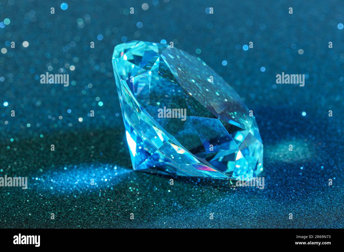Beautiful dazzling diamond on light blue glitter background, closeup ...