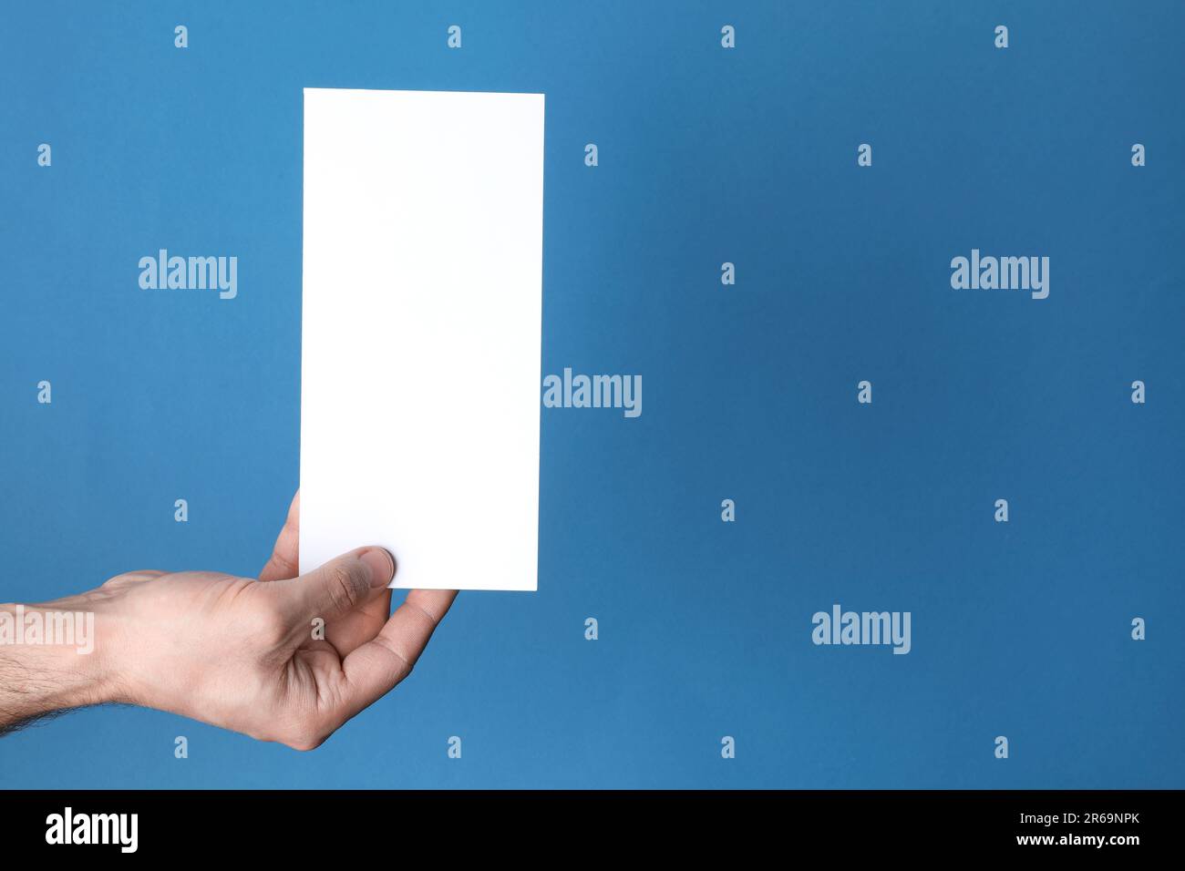 Man holding flyer on blue background, closeup. Mockup for design Stock ...