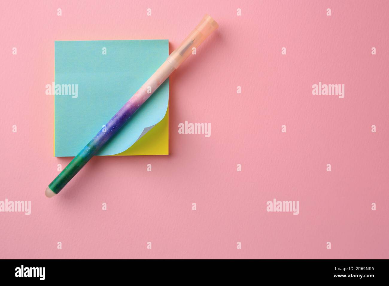Blank paper notes and pen on pink background, top view. Space for text ...