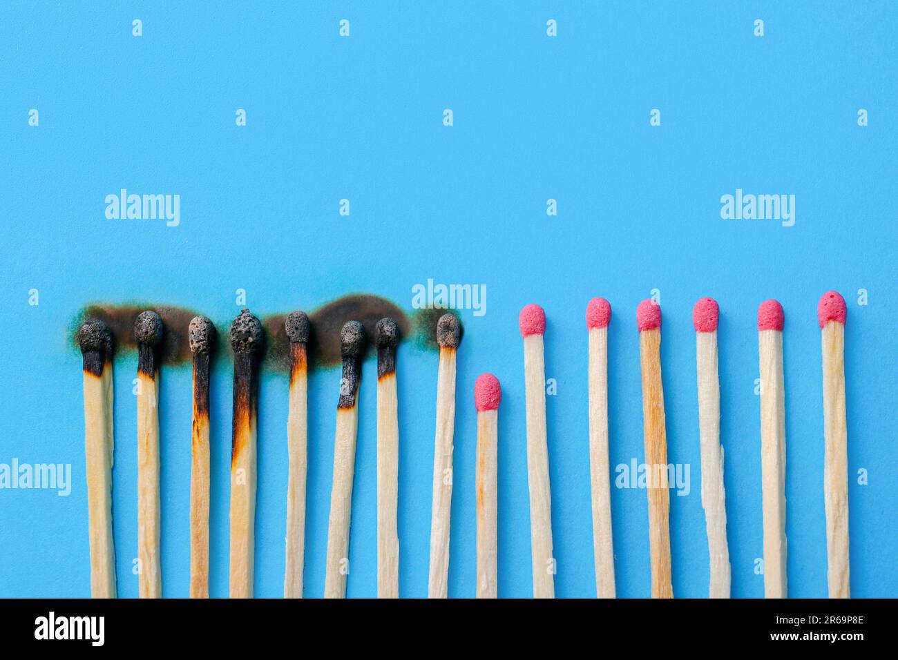 Burnt and whole matches on light blue background, flat lay. Space for ...