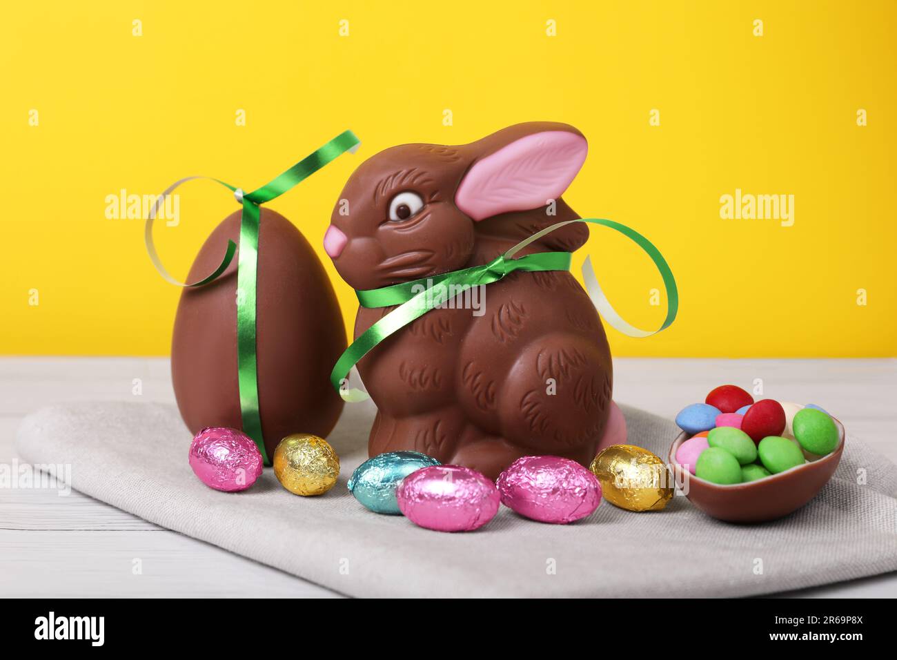 Chocolate Easter bunny, eggs and candies on white wooden table against ...