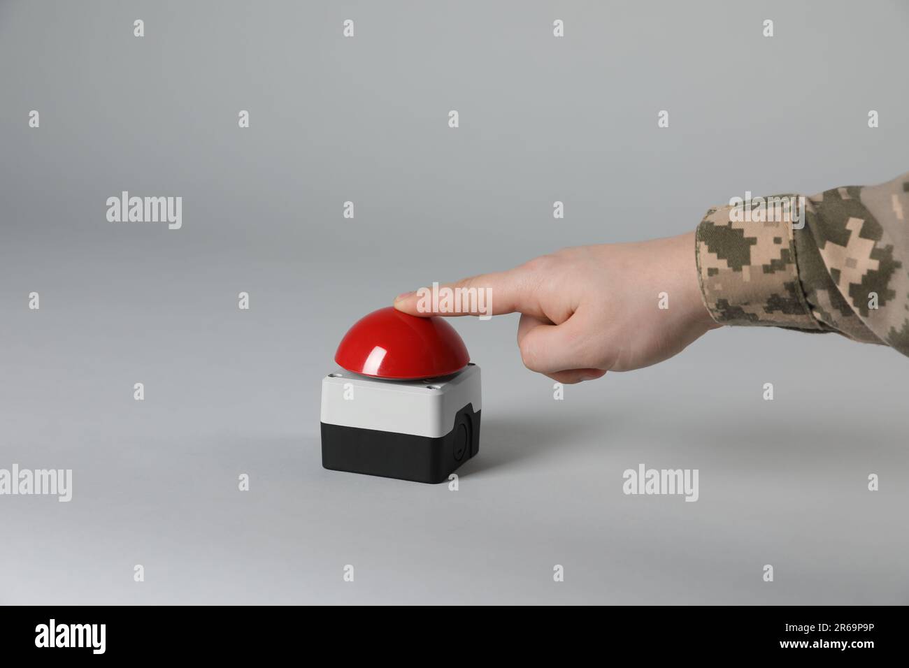 Serviceman pressing red button of nuclear weapon on light gray ...