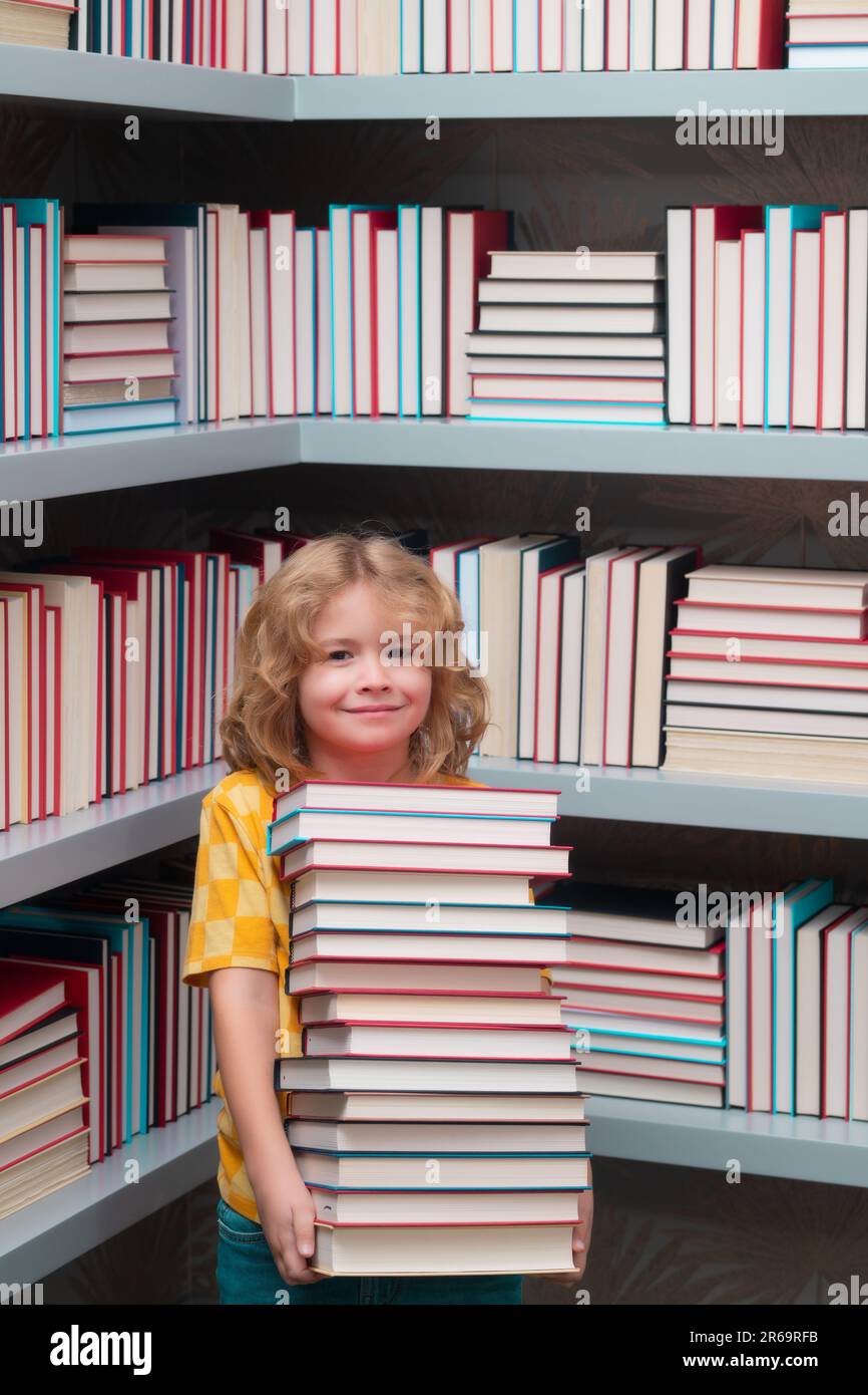 Funny school kid hold stack of books. Child reads books in the library ...