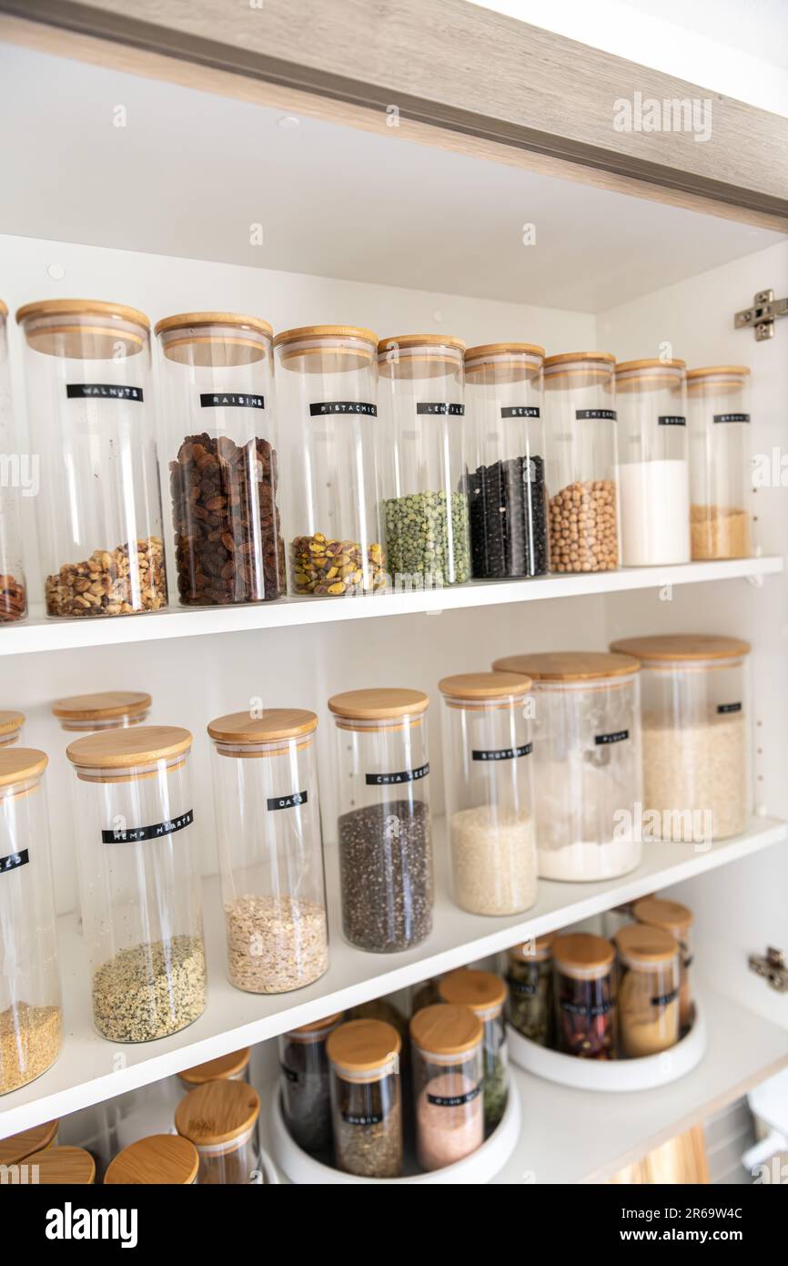 Organized labeled food pantry in a home kitchen with spices grains ...