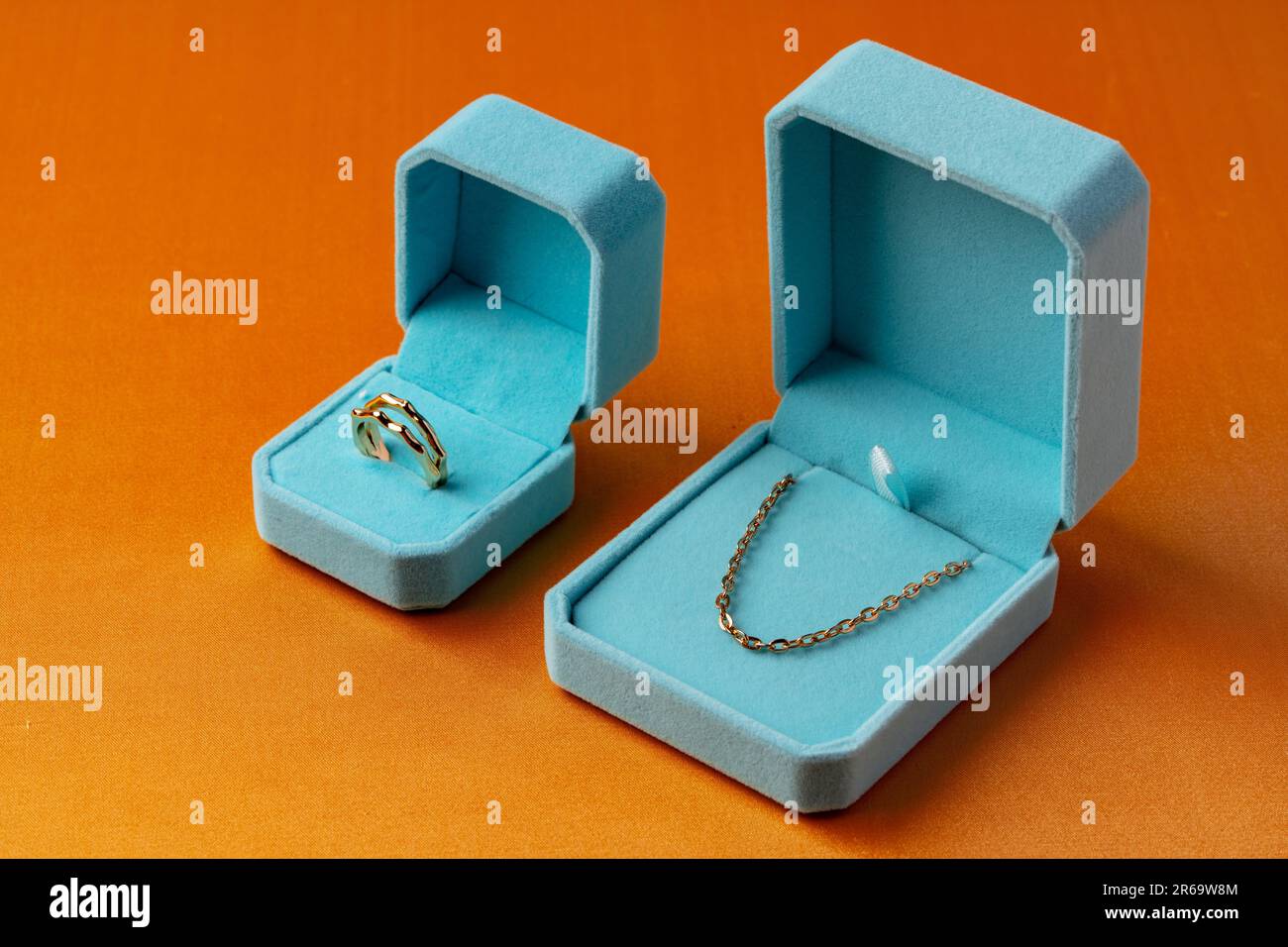Blue boxes with golden jewelry on orange background Stock Photo - Alamy
