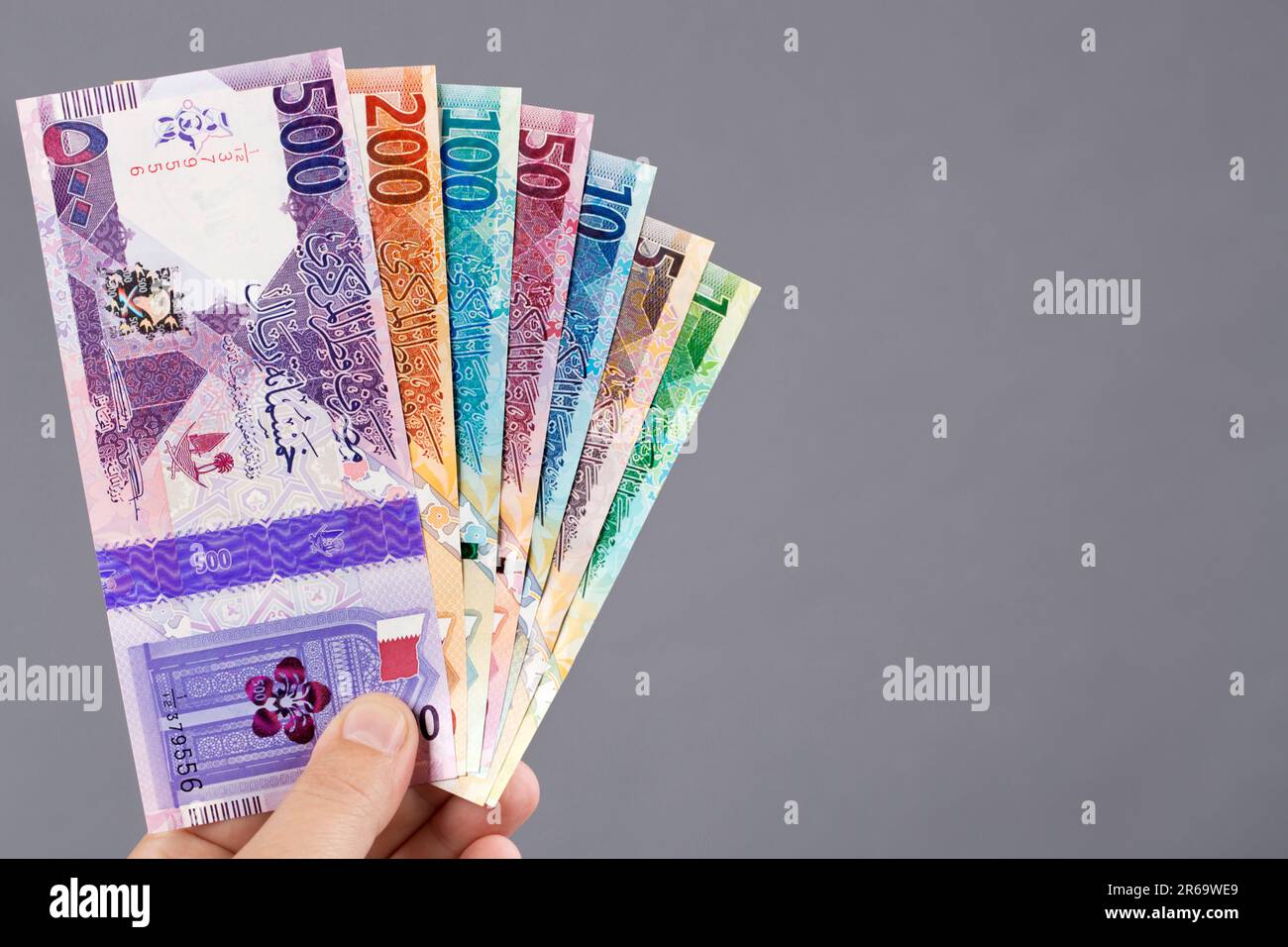 Qatari money - riyal in the hand on a gray background Stock Photo - Alamy