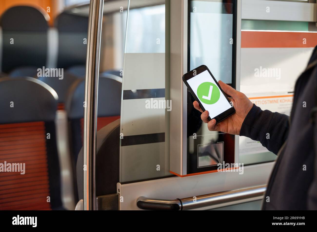 Person buying train ticket with smartphone from ticket machine. Holding ...