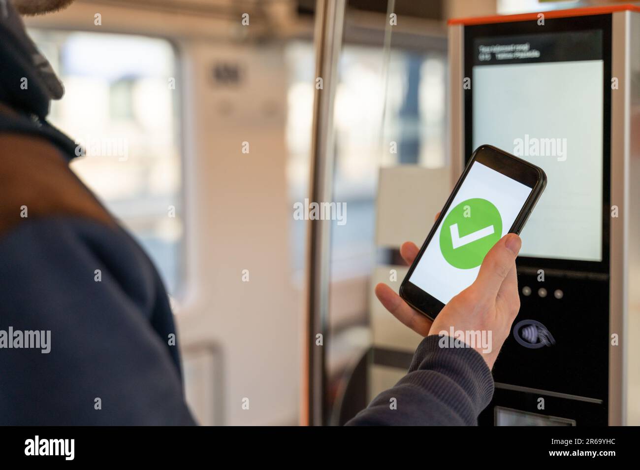 Person buying train ticket with smartphone from ticket machine. Holding ...