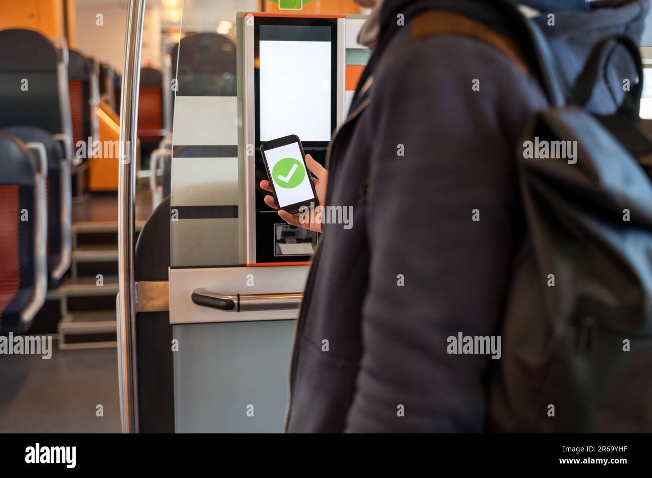 Person buying train ticket with smartphone from ticket machine. Holding ...
