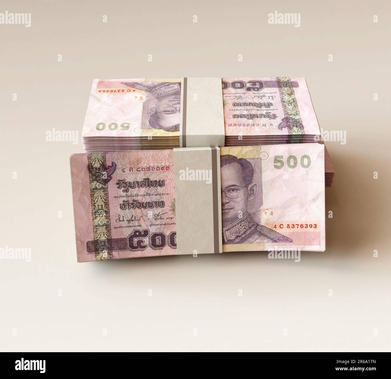 A stack of bundled thai bhat banknotes on an isolated light background ...