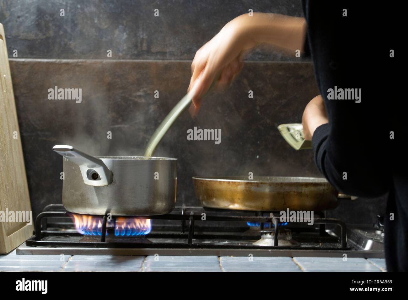 Pan and frying pan on gas hob used for cooking meal hands of cook and ...
