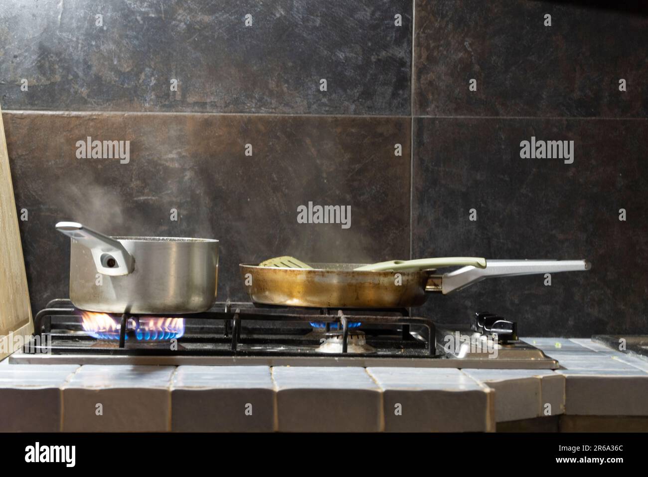 Pan and frying pan on gas hob used for cooking meal hands of cook and ...