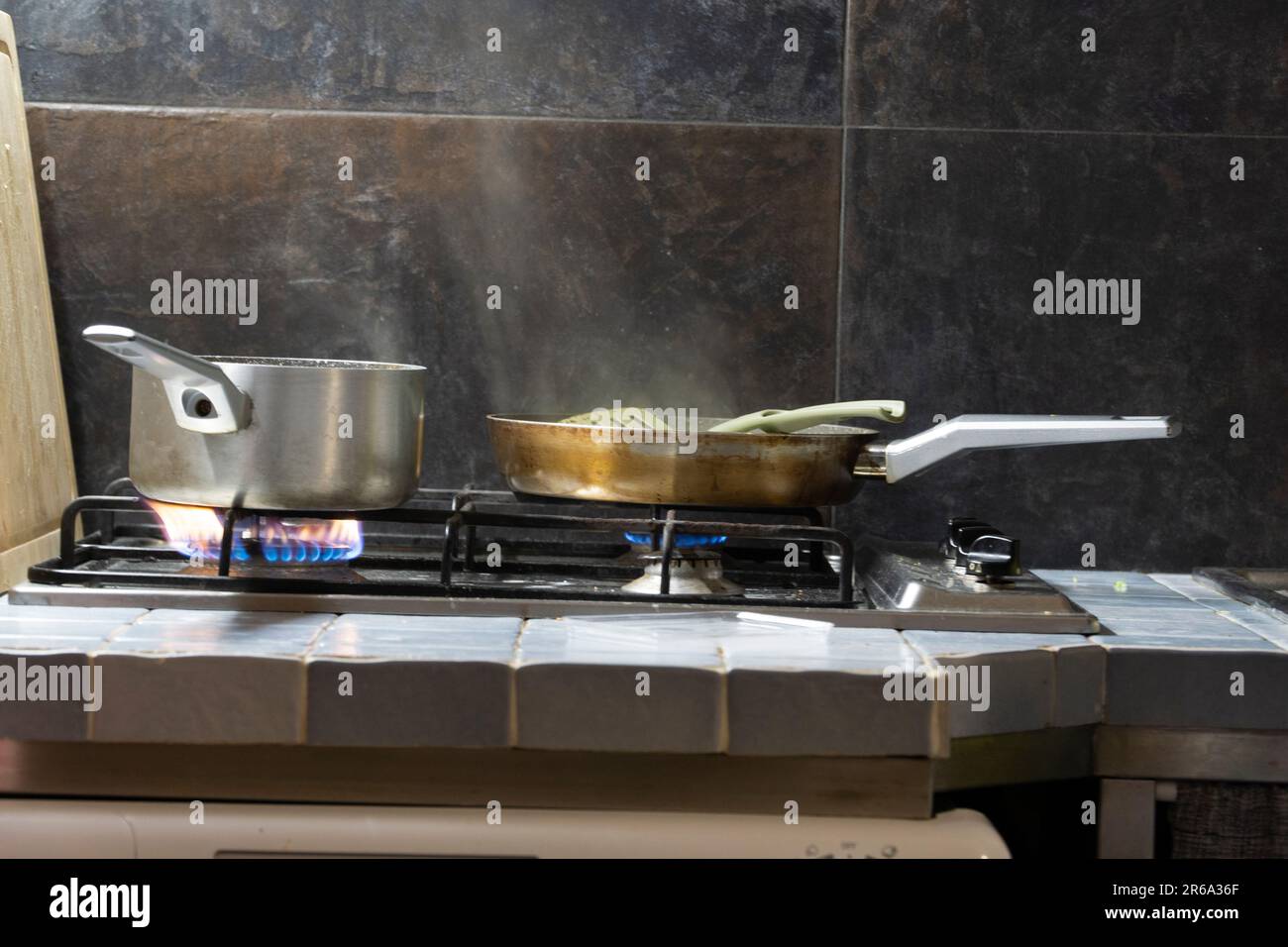 Pan and frying pan on gas hob used for cooking meal hands of cook and ...