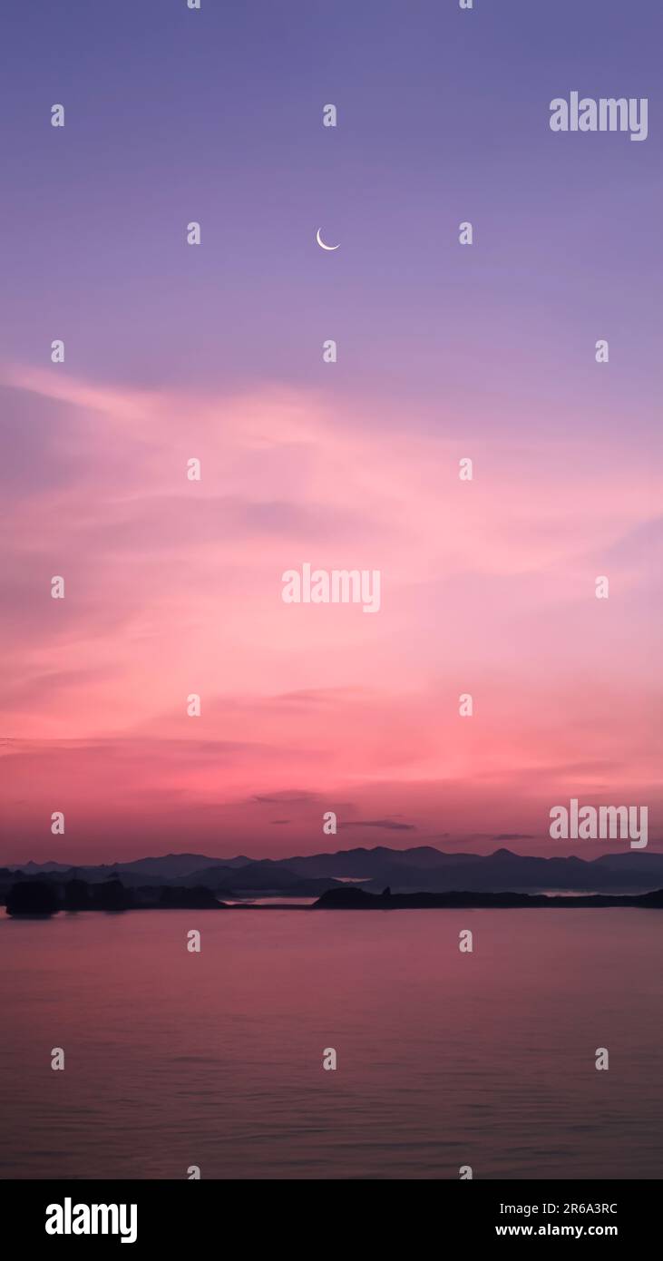 Vertical image, crescent moon in dramatic vibrant color sky with ...