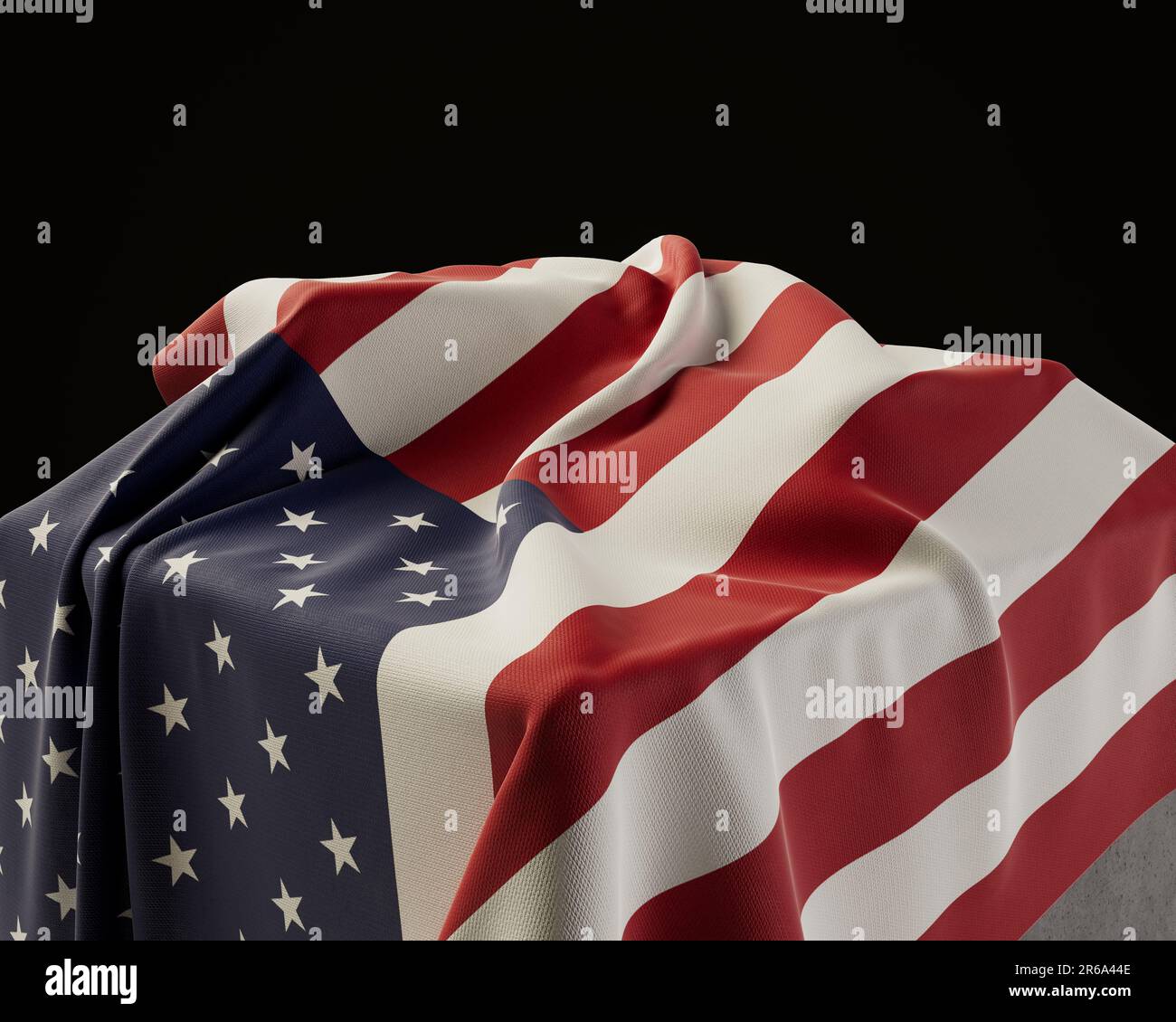 An american flag draped over a stone plinth on an isolated dark studio ...