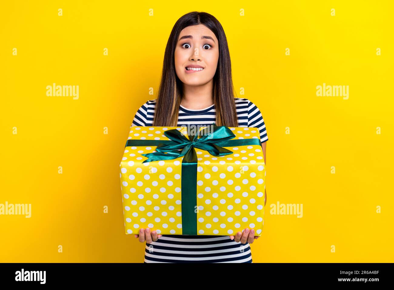 Photo of doubtful unsure lady wear striped dress biting lips holding ...