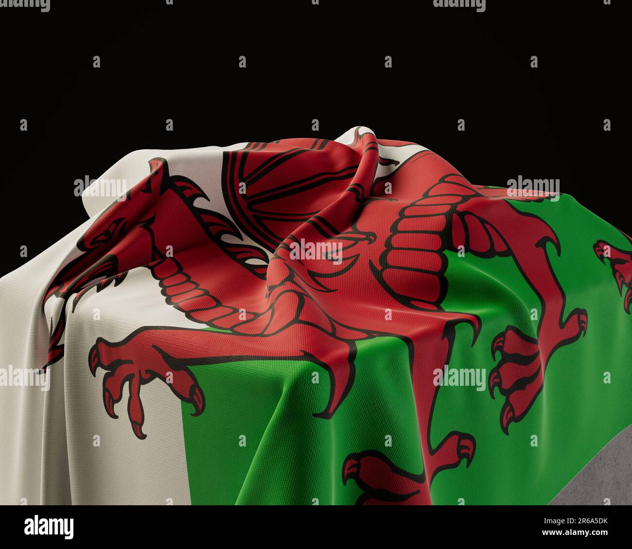 A wales flag draped over a stone plinth on an isolated dark studio ...