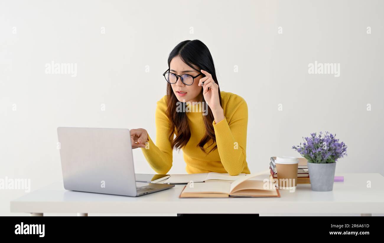 A puzzled and confused young Asian female college student is touching ...