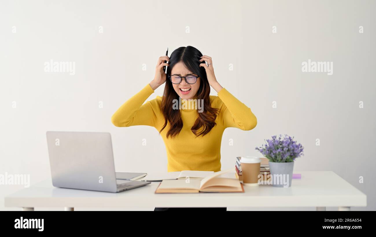 A furious and stressed young Asian female college student is pulling ...