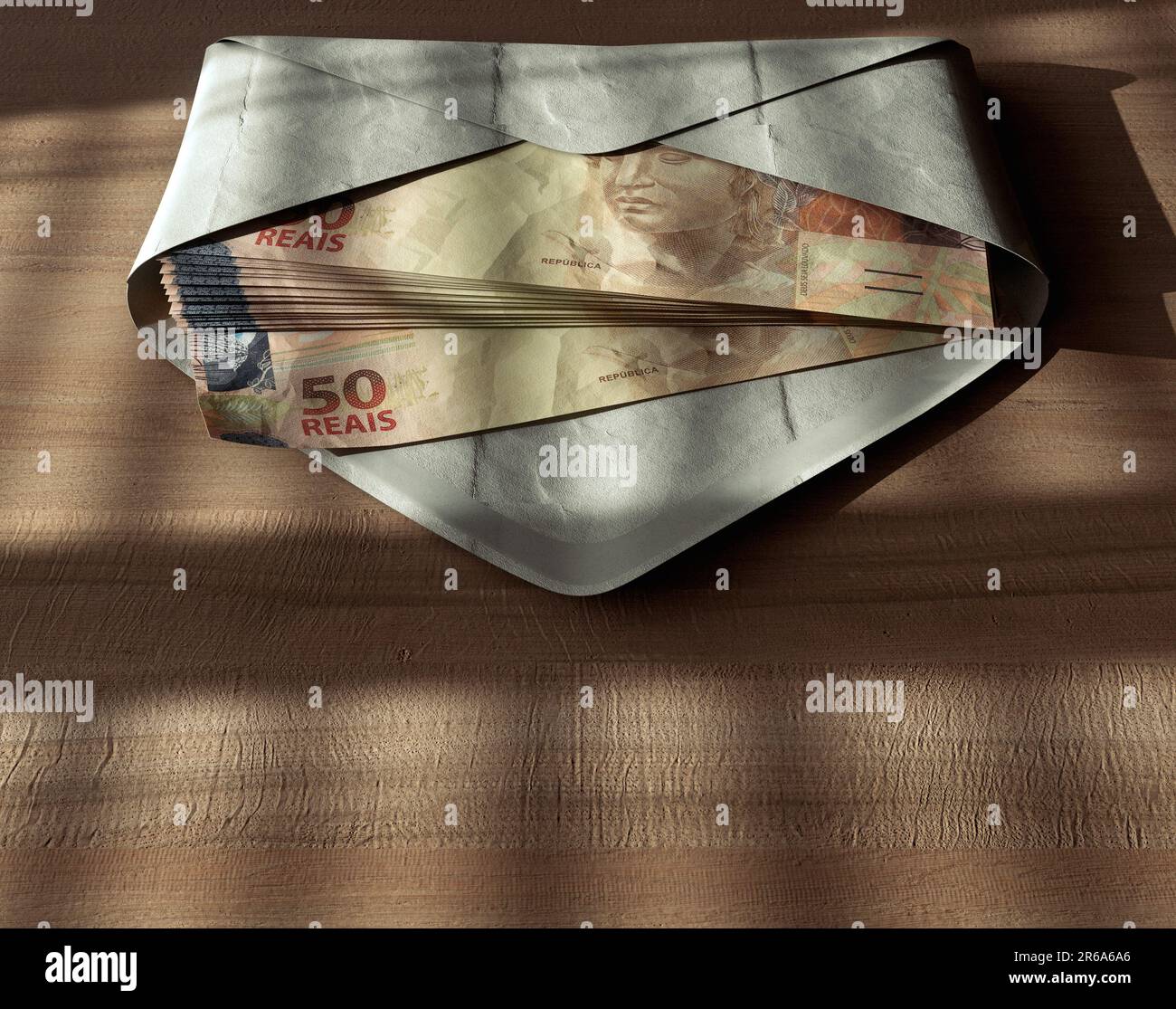 A spreading pile of real banknotes in an envelope on a wooden surface ...