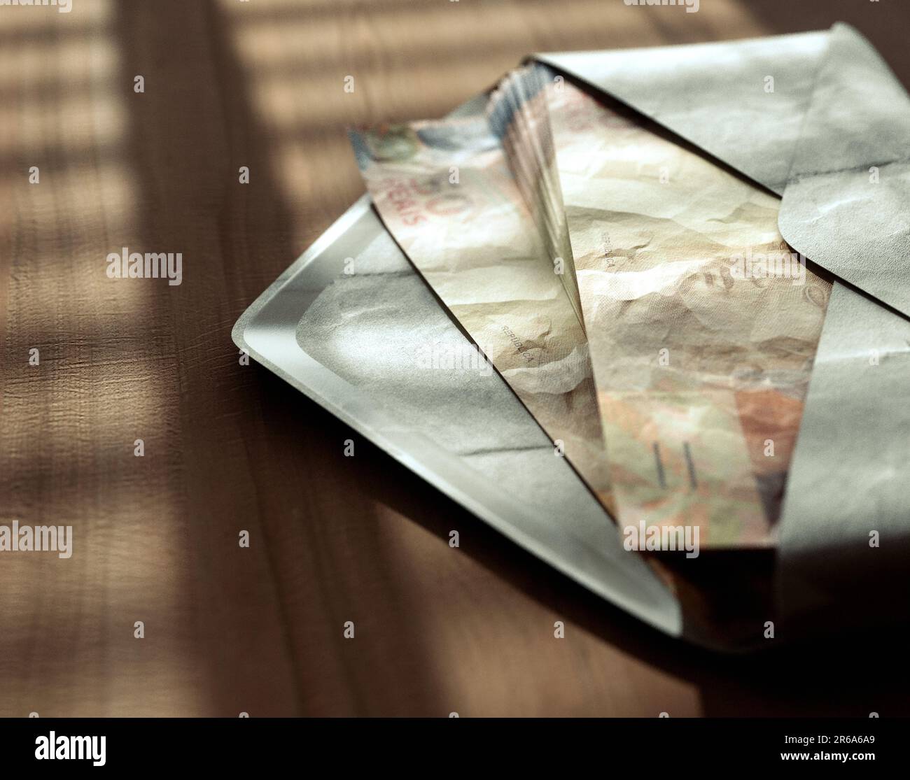 A spreading pile of real banknotes in an envelope on a wooden surface ...